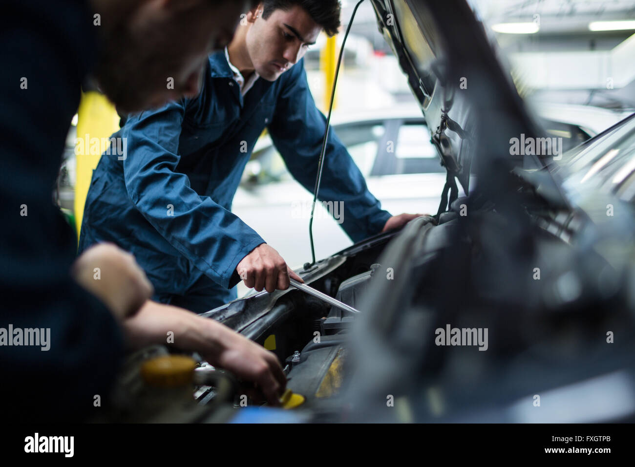 Mechanics examining car engine Stock Photo - Alamy