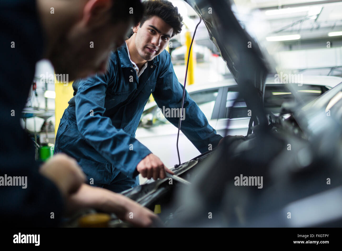 Mechanics examining car engine Stock Photo - Alamy