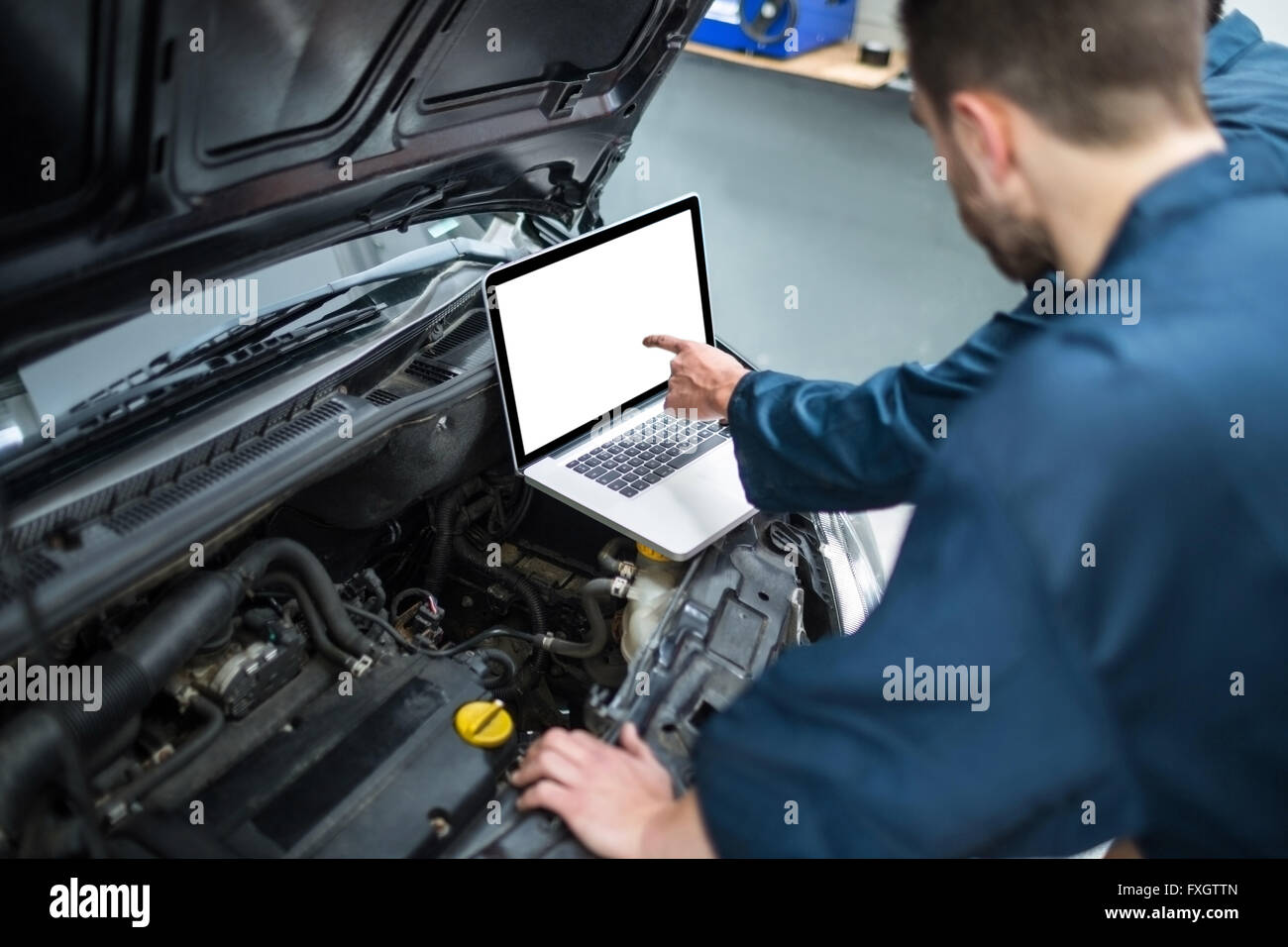 Mechanics examining car engine using laptop Stock Photo - Alamy