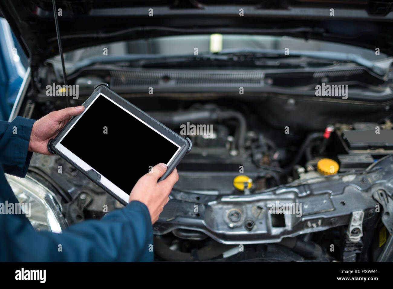 Mechanic holding diagnostic tool at the repair garage Stock Photo - Alamy