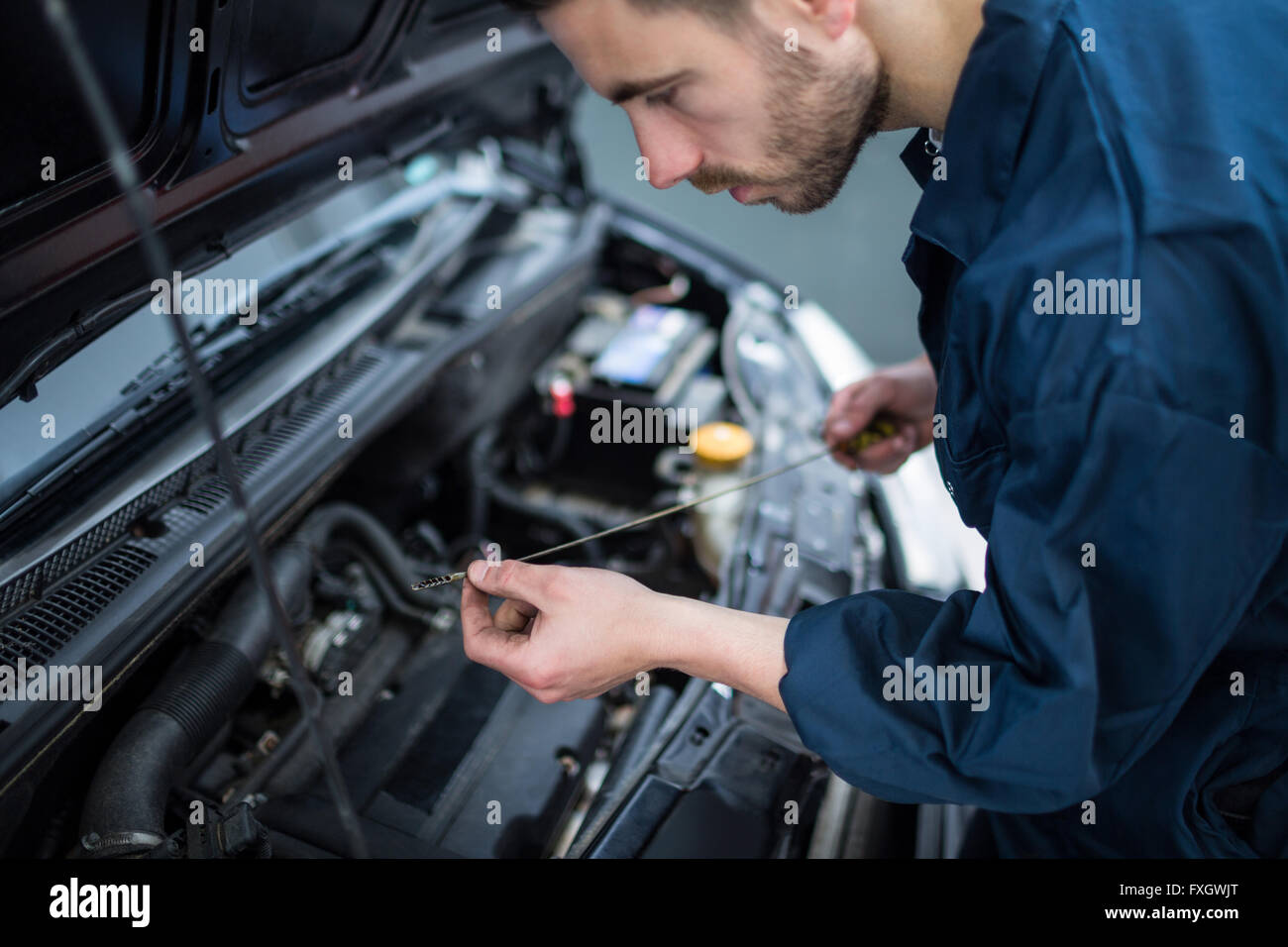 Mechanic checking the oil level in a car engine Stock Photo - Alamy