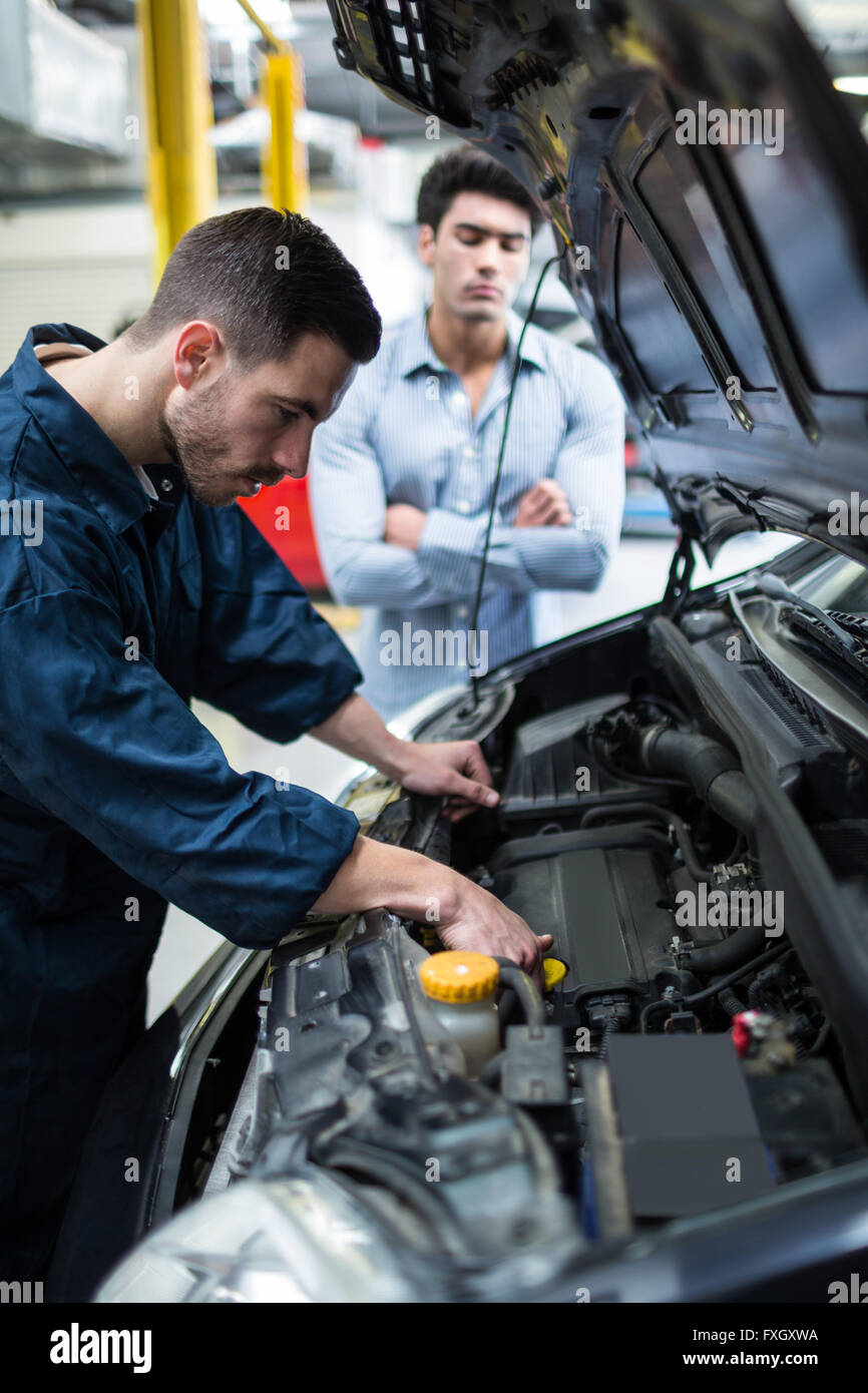 Mechanic examining car engine while customer standing and looking Stock ...