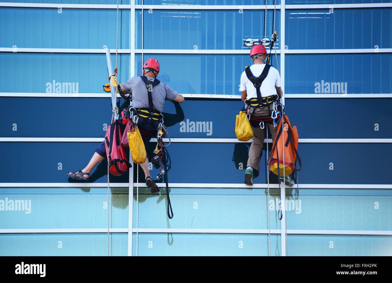 Two construction workers working at height on modern commercial ...