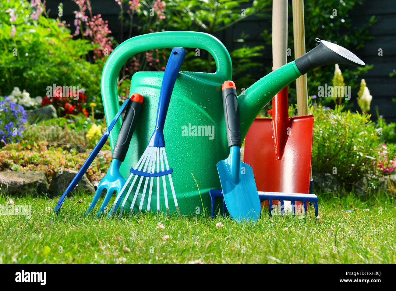 Watering can and tools in the garden Stock Photo - Alamy