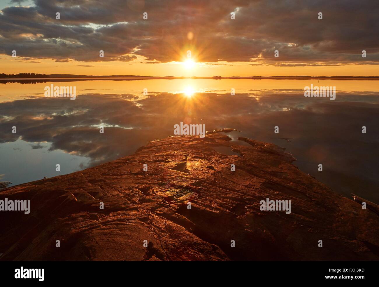 Warm and vibrant golden sunset with red color on the rocks of the shore ...
