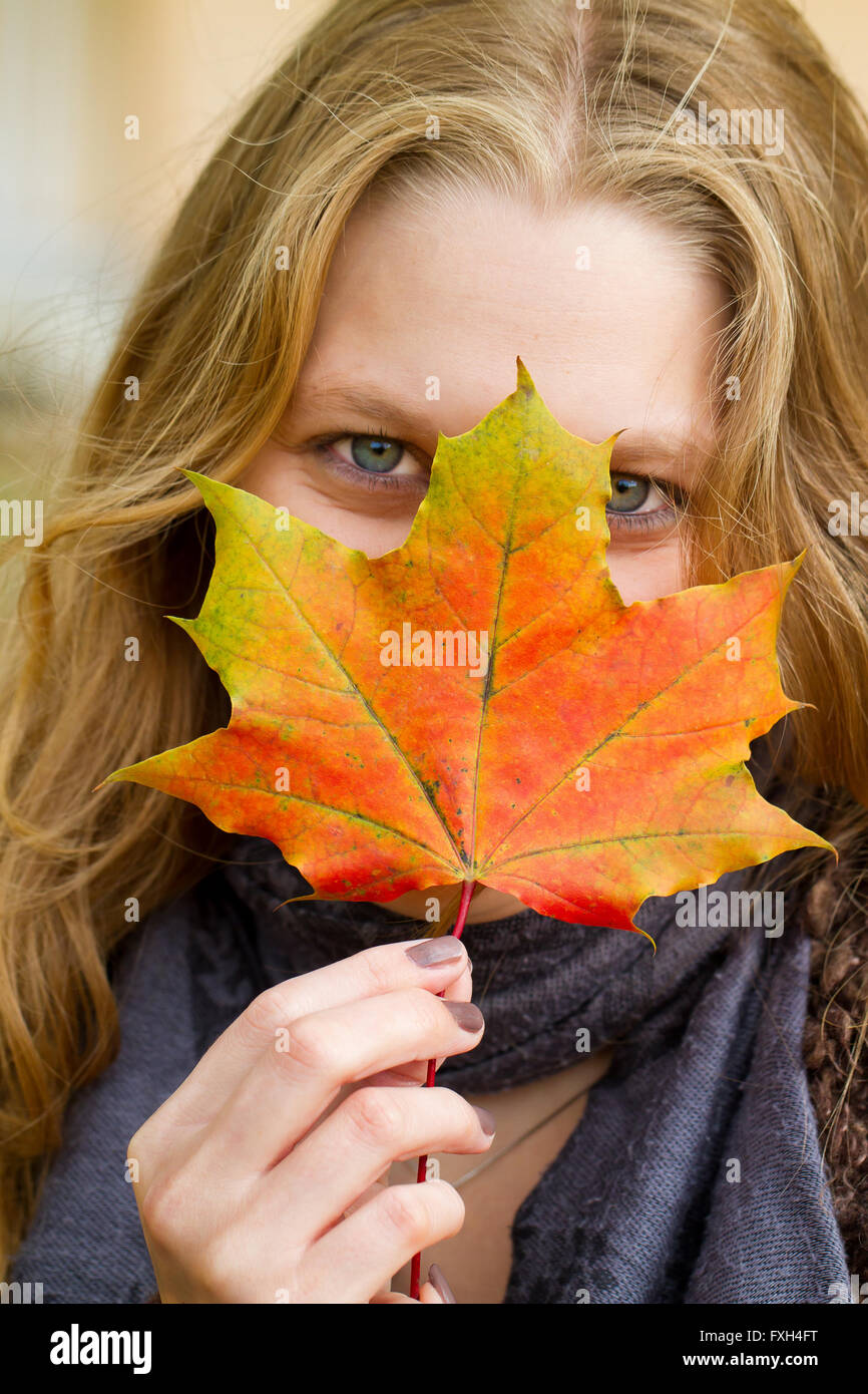 Young woman with colorful maple leaf covered her face Stock Photo - Alamy