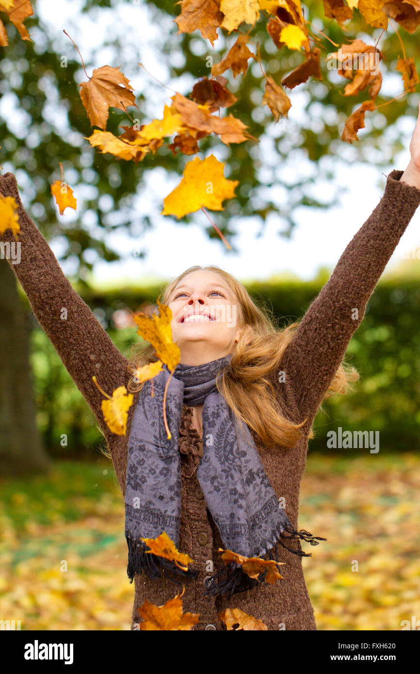Autumn leaves falling on happy young woman in forest Stock Photo - Alamy