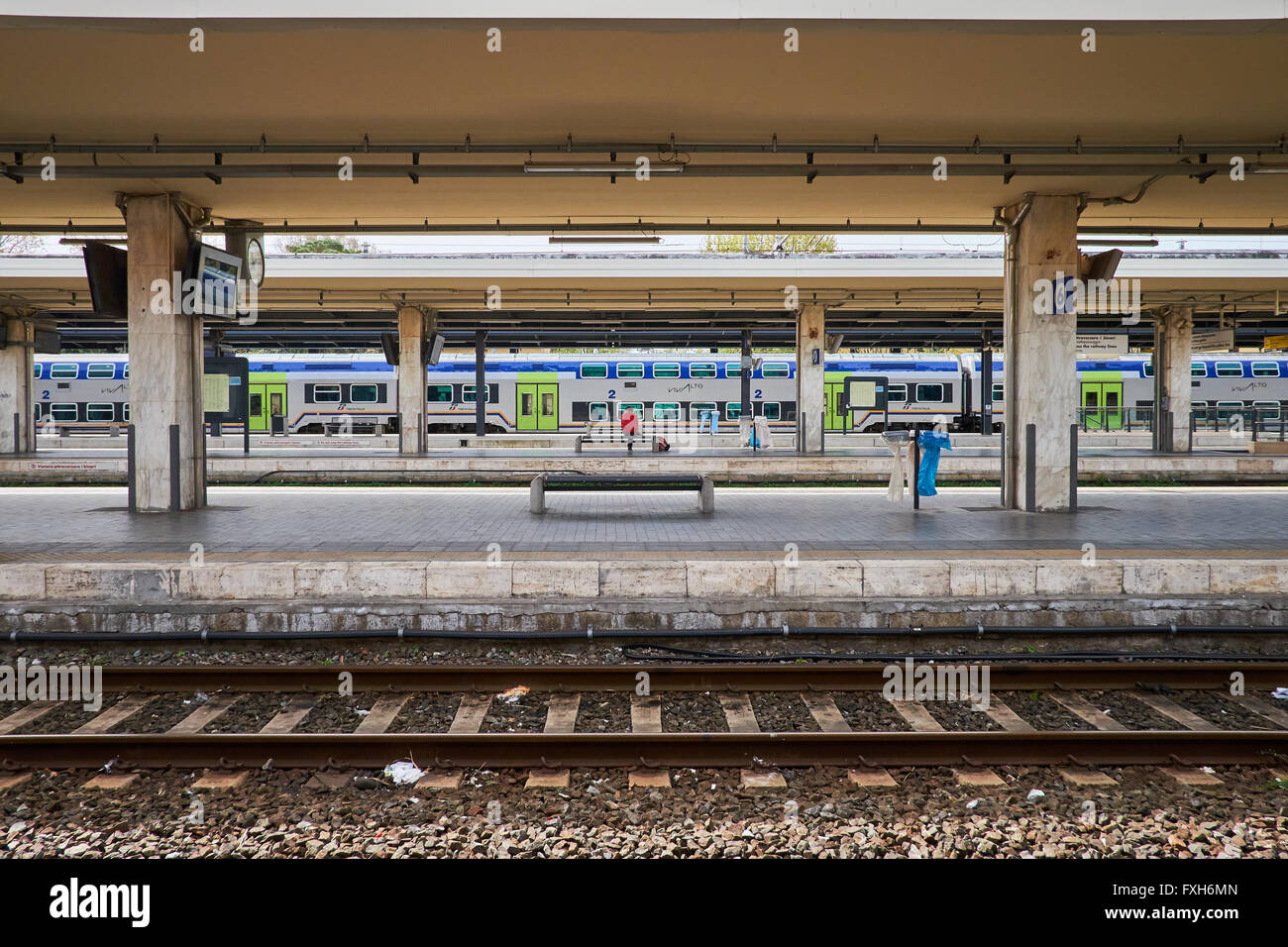 Single person seated on a platform at a train station with a train at a ...