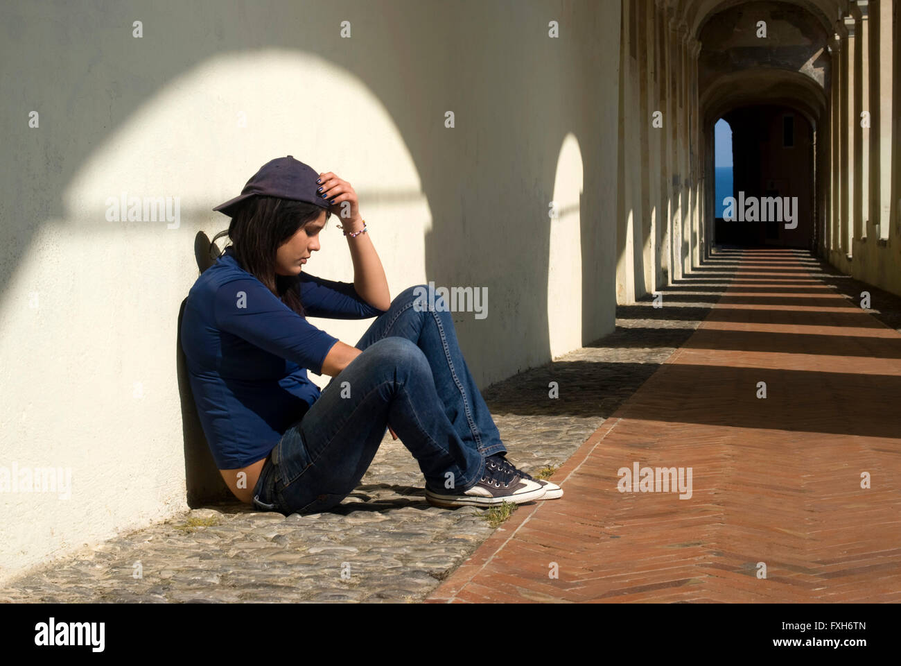 Girl sitting against wall Stock Photo - Alamy