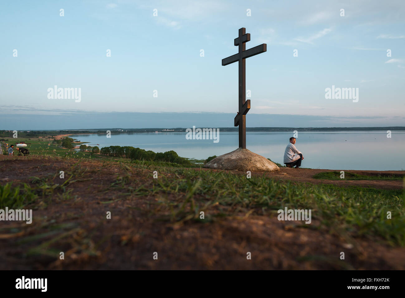 The unknown sits under a Christian cross and darts a glance back Stock ...
