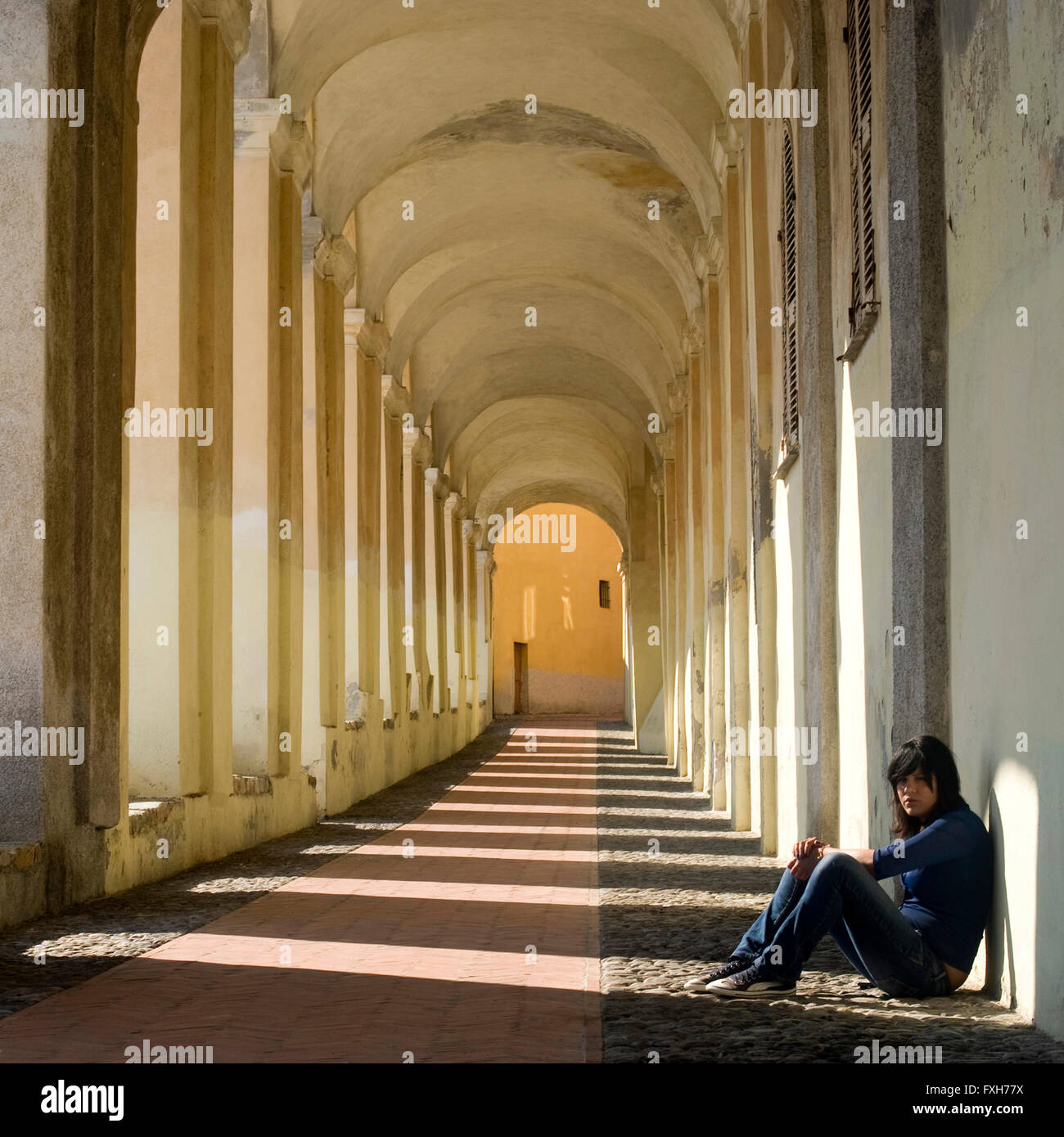 Girl sitting against wall Stock Photo - Alamy