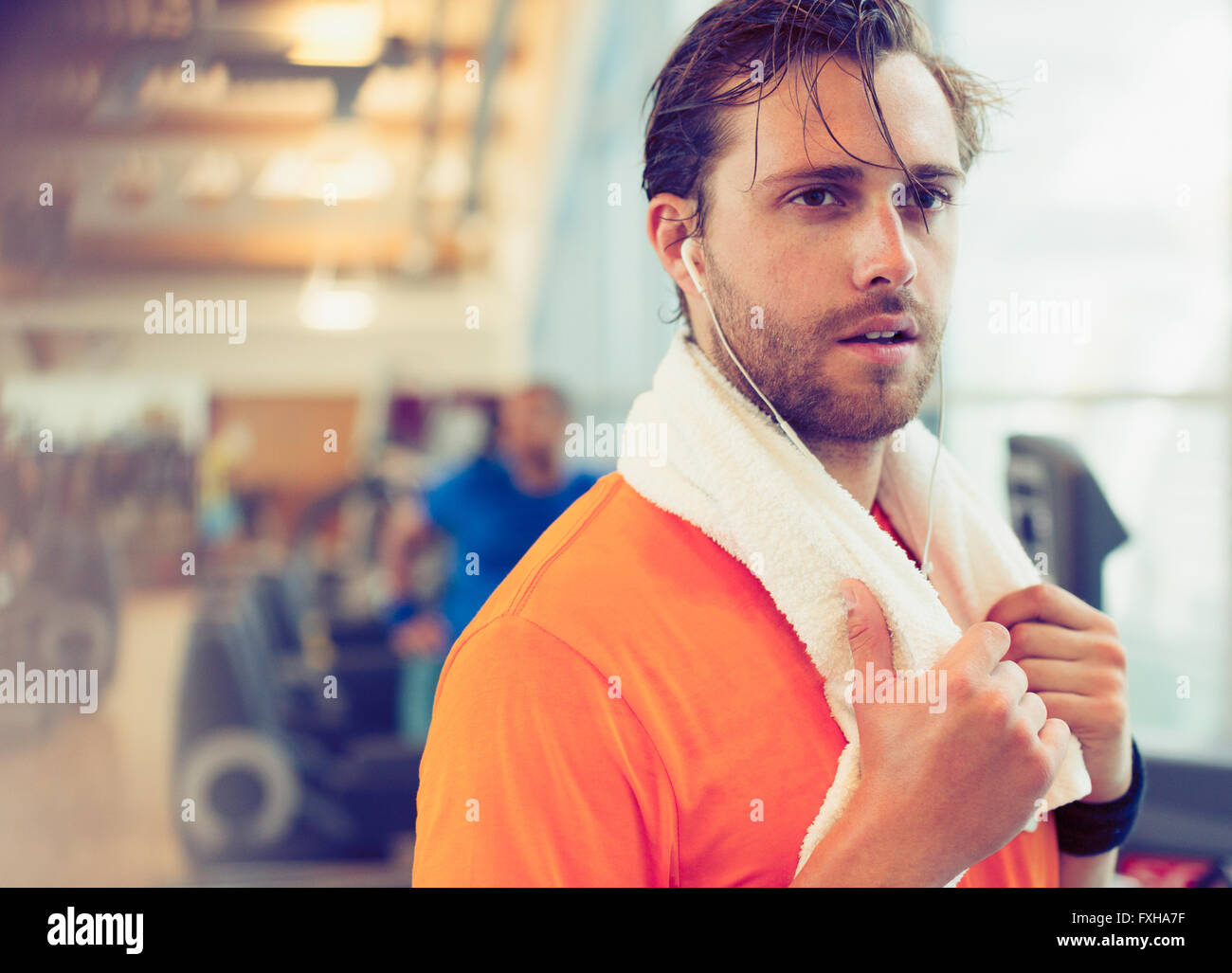 Sweating man with towel and headphones resting in gym Stock Photo - Alamy