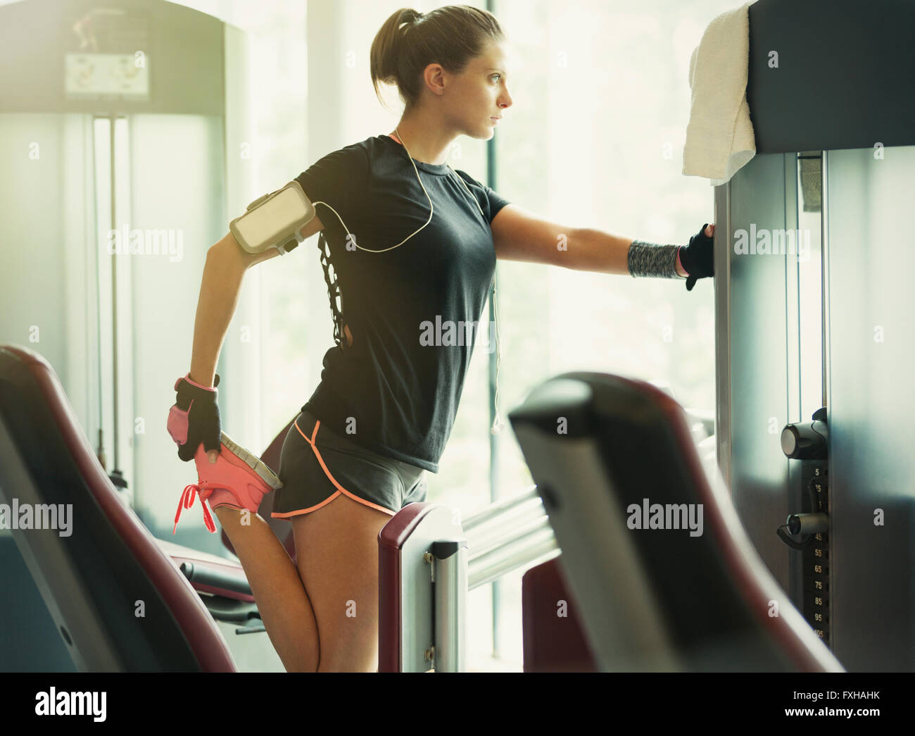 Focused woman stretching leg at exercise equipment in gym Stock Photo ...