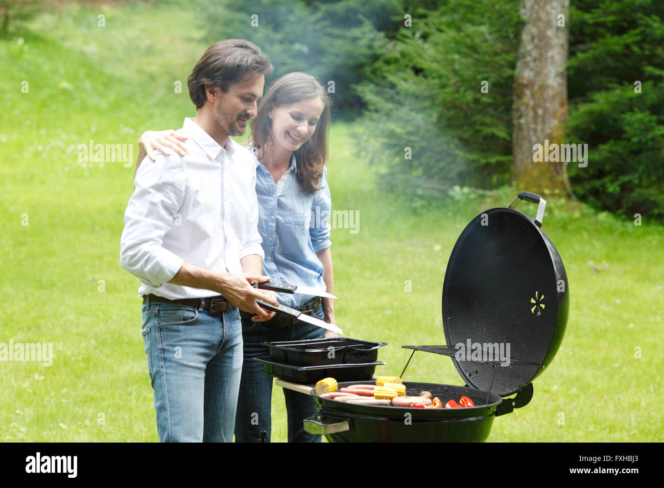 Happy couple cooking food on barbecue Stock Photo - Alamy
