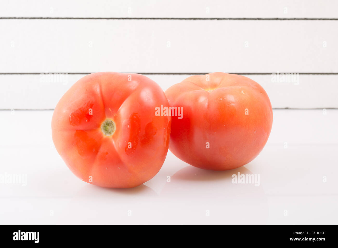 Two ripe tomatoes on a light background propped up Stock Photo - Alamy