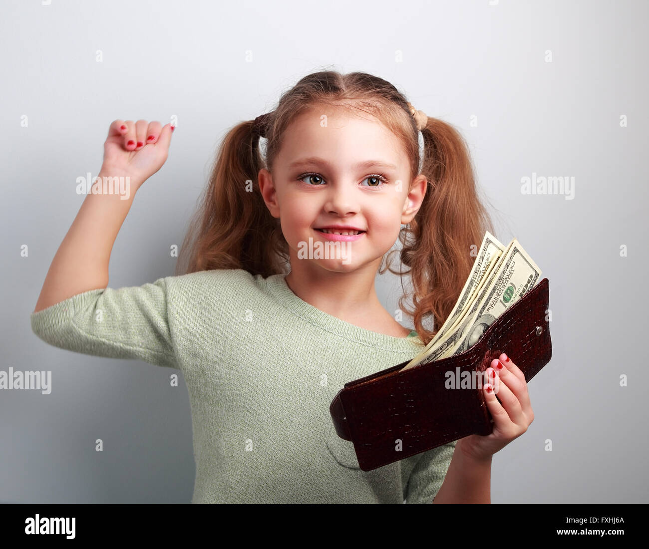 Successful winner kid girl holding wallet with much money on blue ...