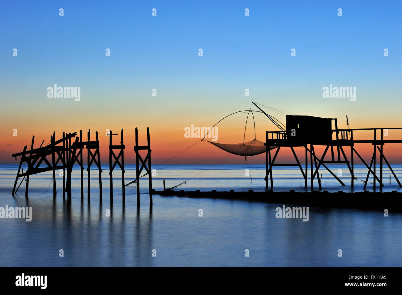 Traditional carrelet fishing hut with lift net on the beach at sunset ...