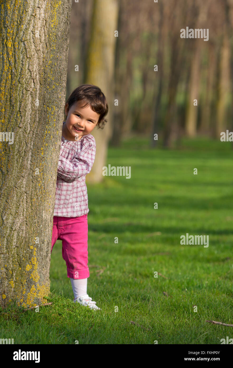 little girl playing hide and seek in the park Stock Photo - Alamy