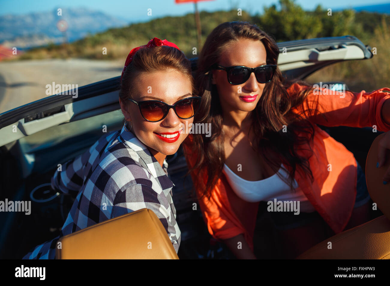 Two young happy girls having fun in the cabriolet outdoors, summer ...