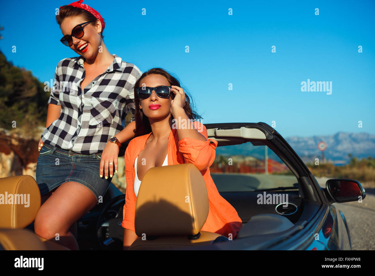 Two young happy girls having fun in the cabriolet outdoors, summer ...