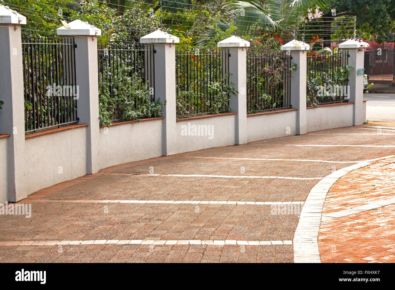 Patterned paved entrance lined by walled security fence Stock Photo - Alamy