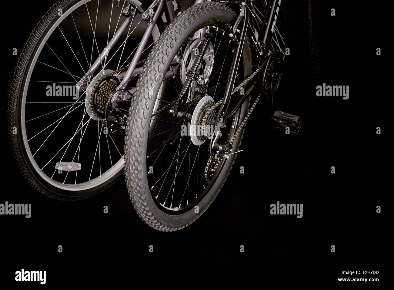Rear wheels and gears of two bicycles side by side isolated on black ...