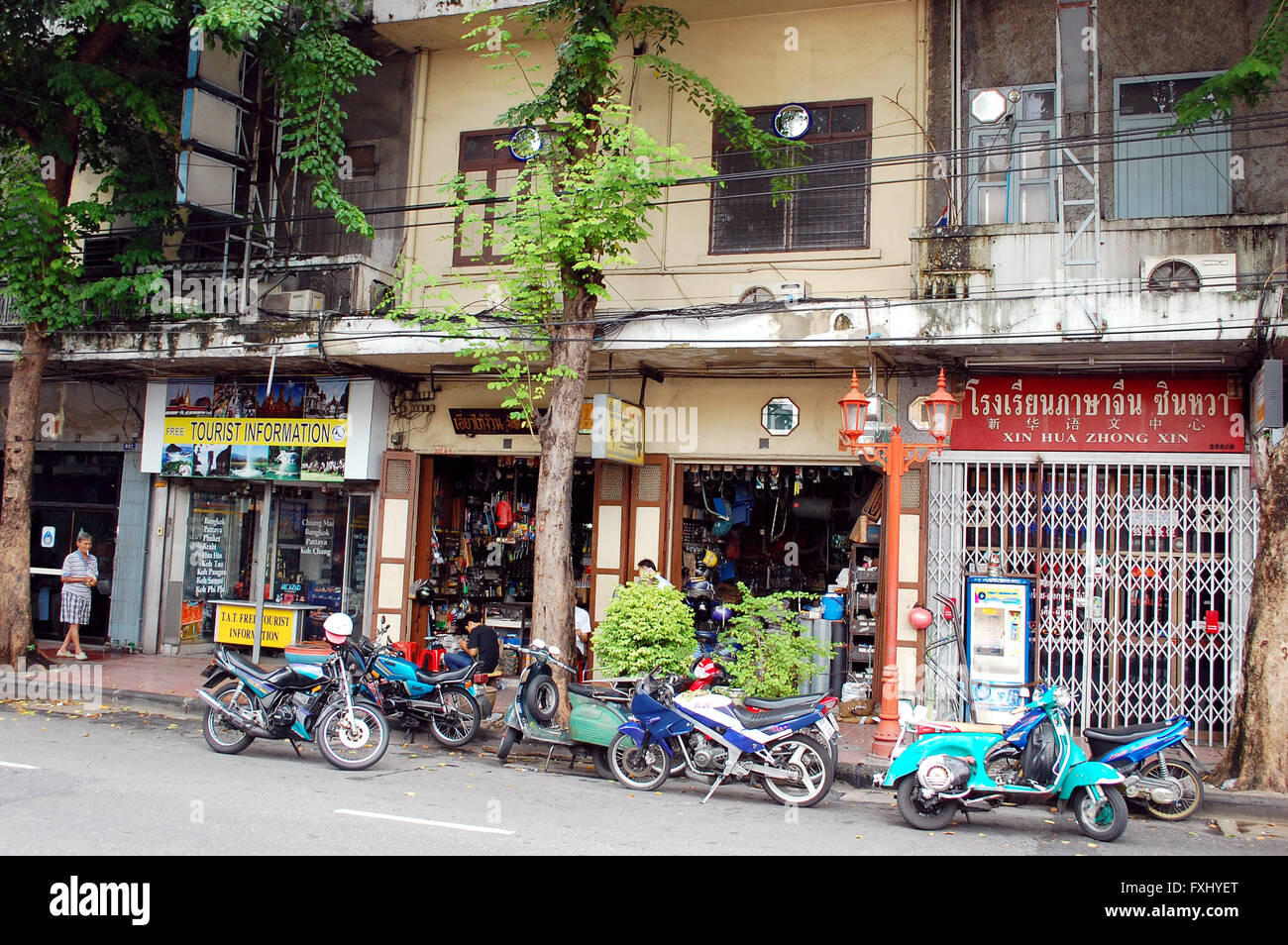 Thai street in china town, with small shops, scooters and motorbikes ...