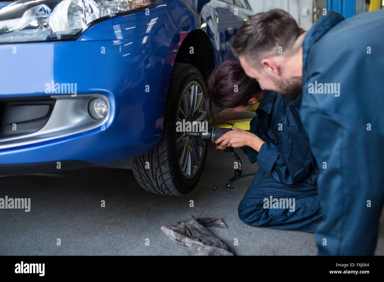 Mechanics fixing a car wheel Stock Photo - Alamy