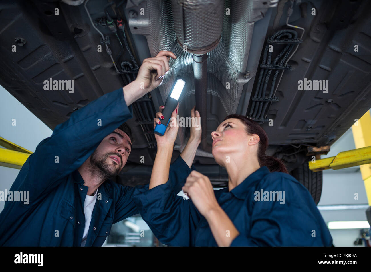 Mechanics examining car using flashlight Stock Photo - Alamy