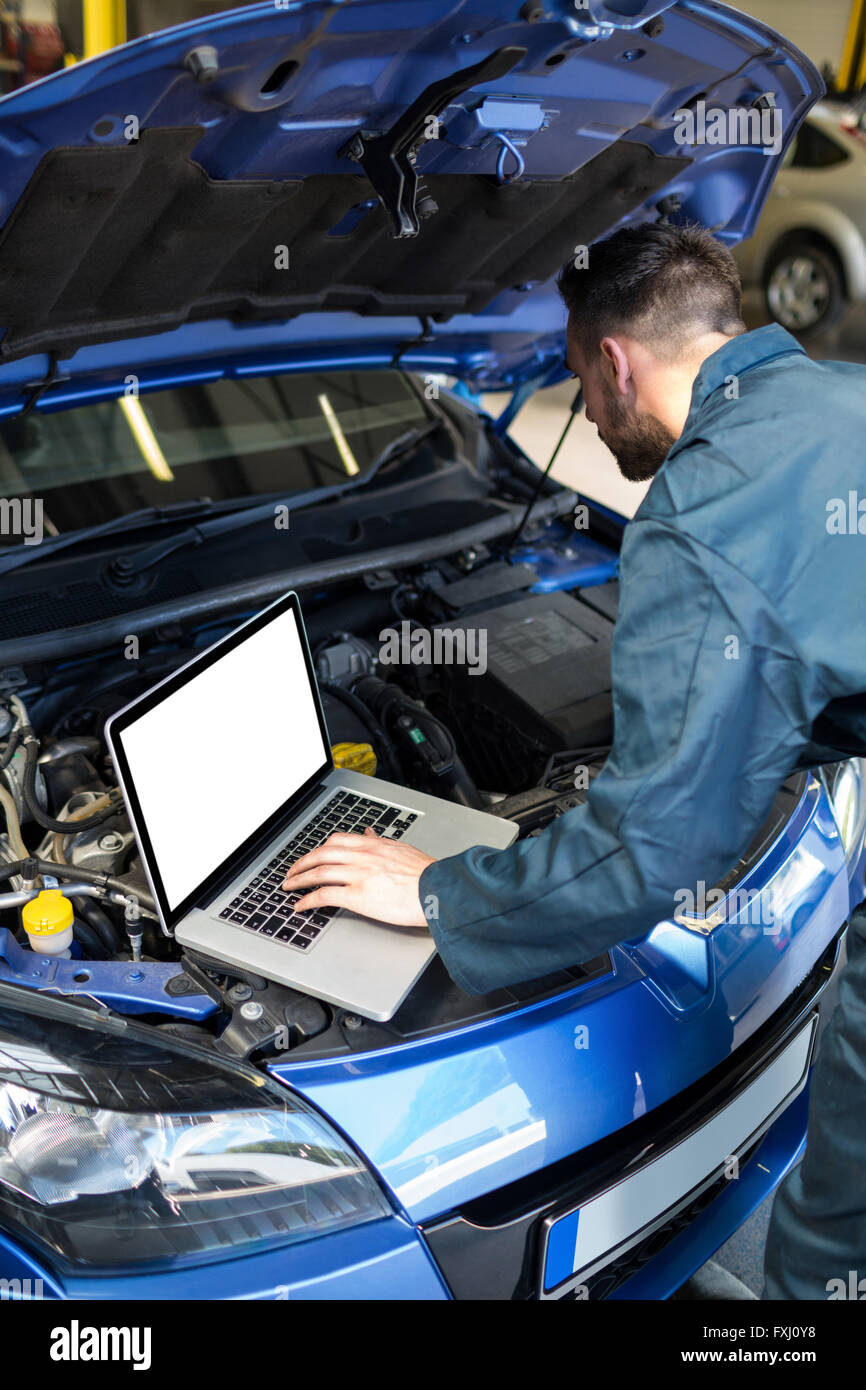 Mechanic examining car engine with help of laptop Stock Photo - Alamy