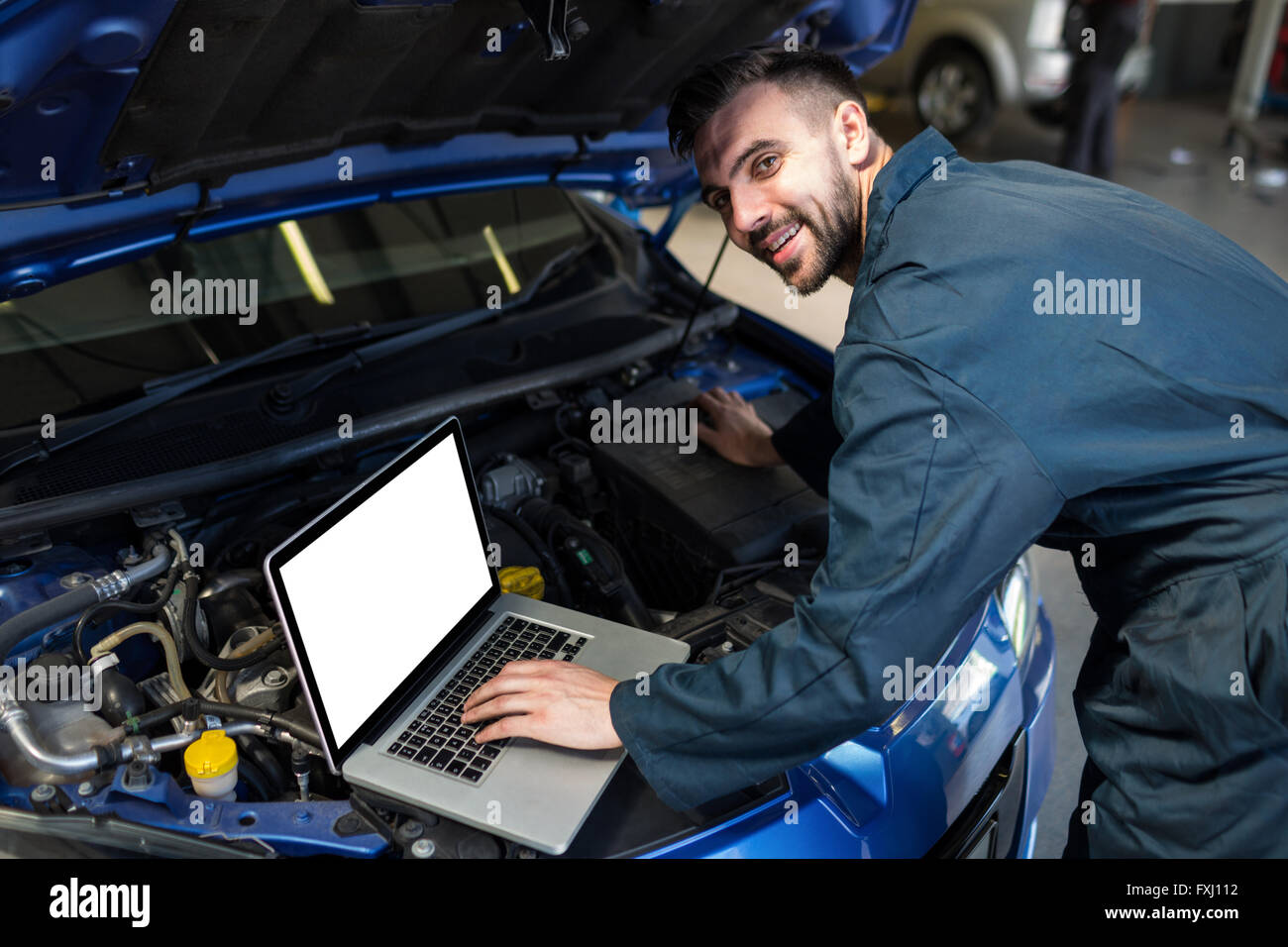 Mechanic examining car engine with help of laptop Stock Photo - Alamy
