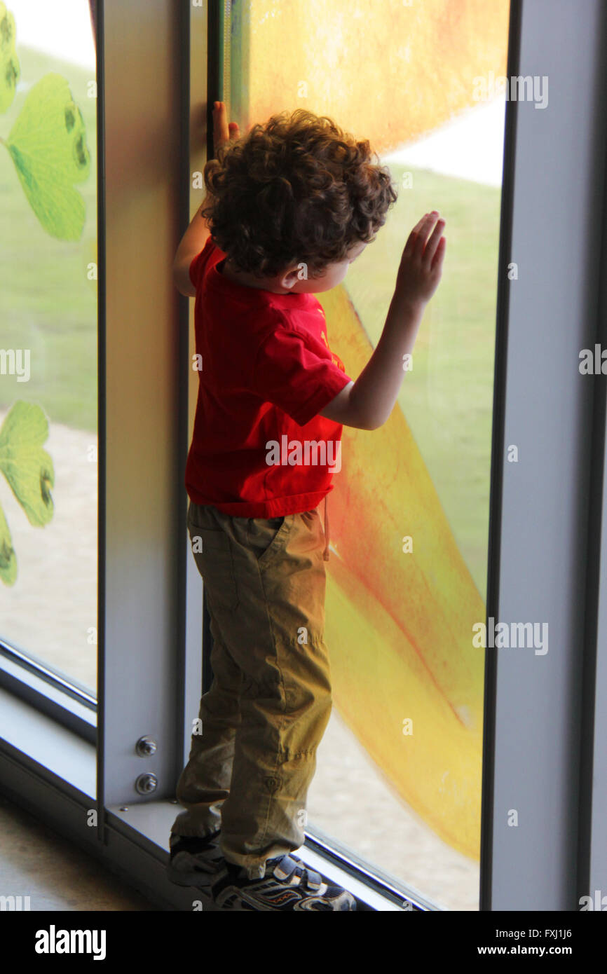 Kid looking through a window Stock Photo - Alamy