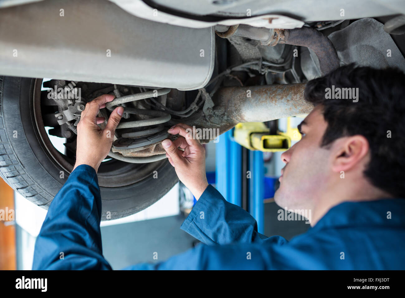 Close-up of mechanic repairing suspension of a car at the repair garage ...
