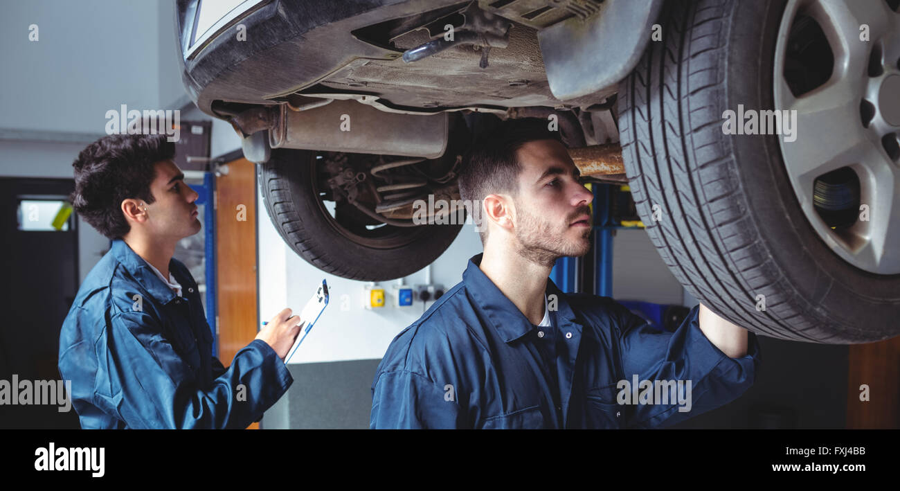 Mechanic fixing a wheel while a colleague preparing a check list Stock ...