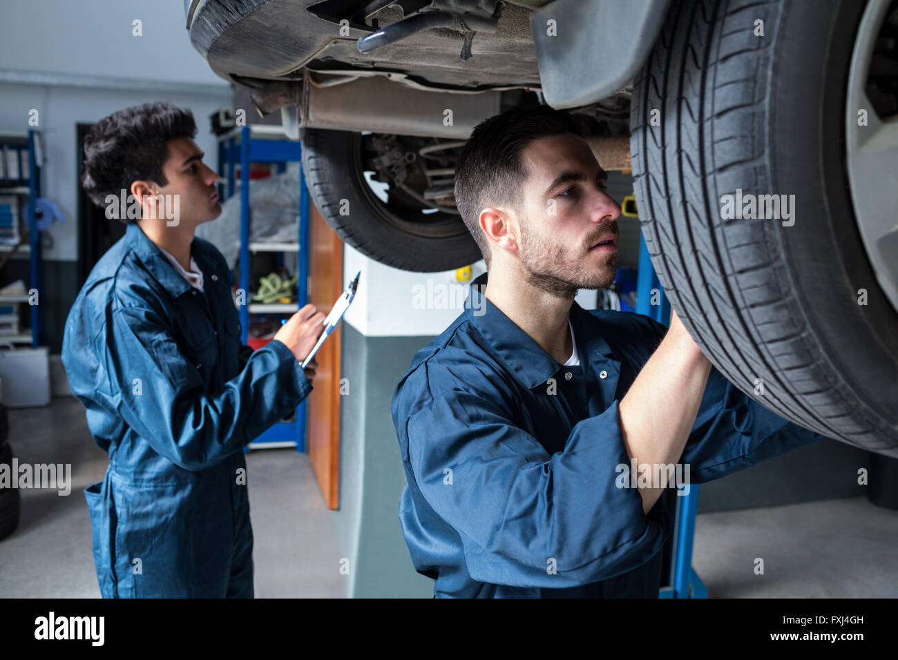 Mechanic fixing a wheel while a colleague preparing a check list Stock ...