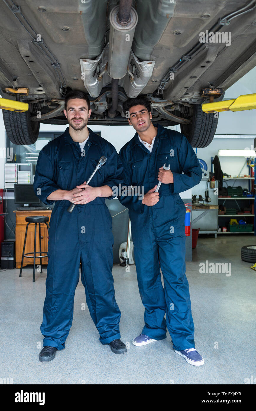 Mechanics holding work tool standing under a car Stock Photo - Alamy