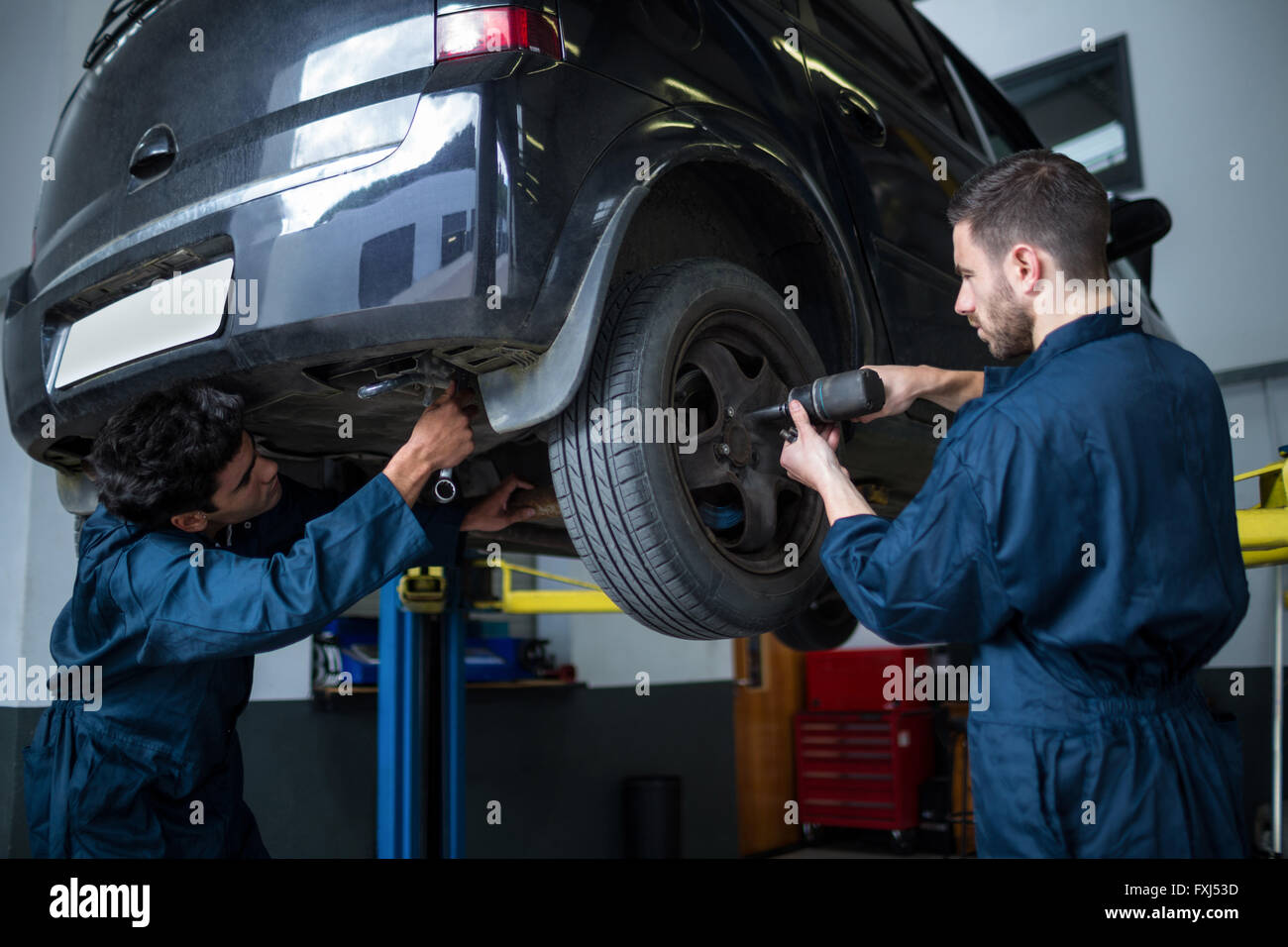 Mechanics fixing a car wheel Stock Photo - Alamy