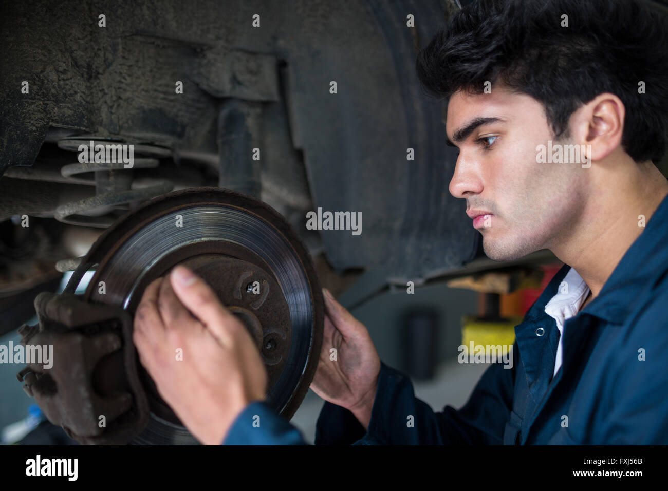 Mechanic examining car brake Stock Photo - Alamy
