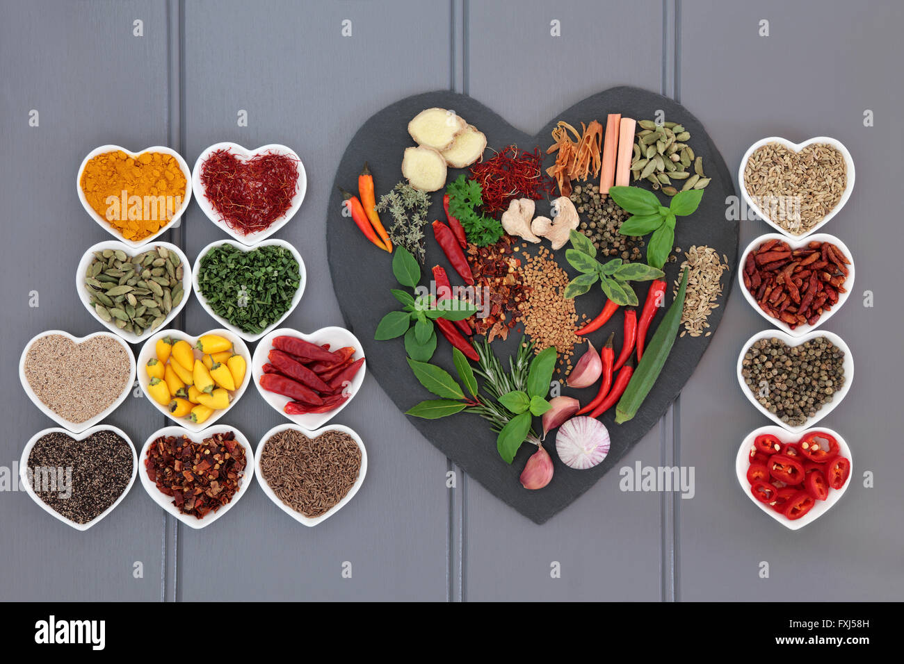 Spice and herb collection on heart shaped slate and in porcelain dishes ...