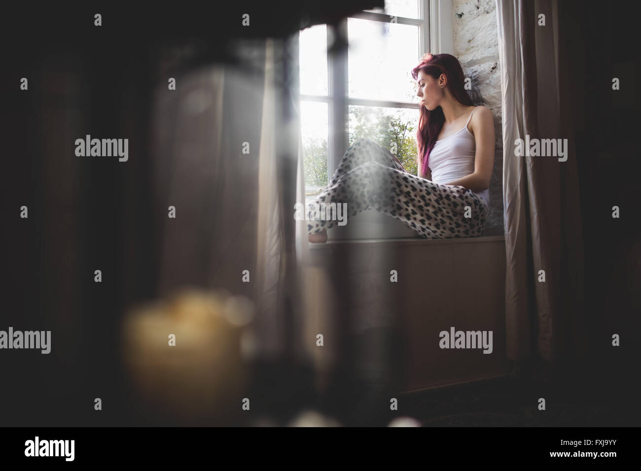 Young woman sitting on the window sill Stock Photo - Alamy