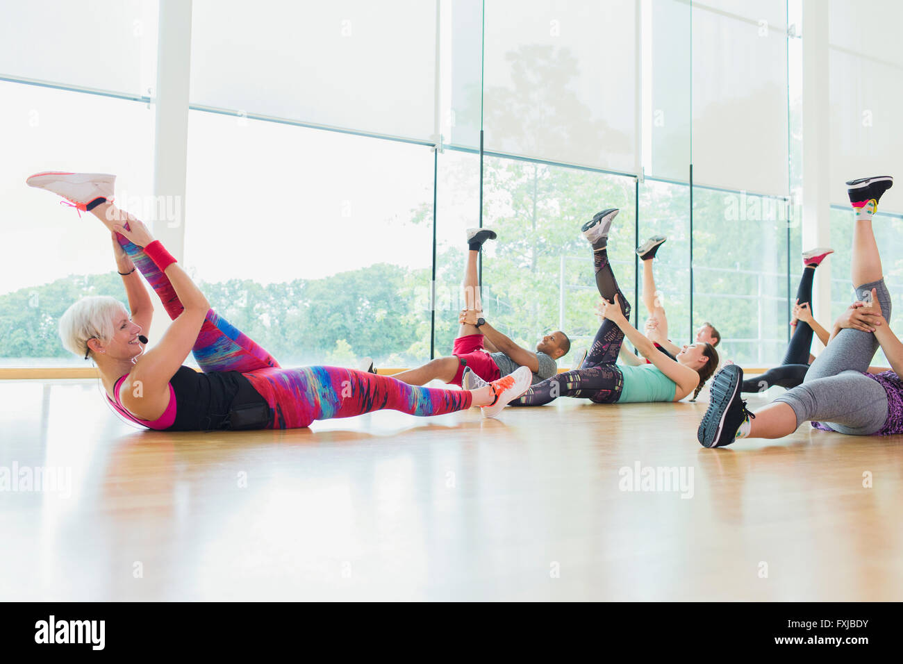 Fitness instructor guiding exercise class stretching legs Stock Photo ...