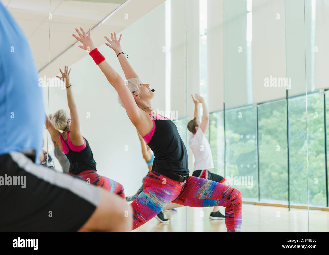 Fitness instructor leading aerobics class in high lunge Stock Photo - Alamy
