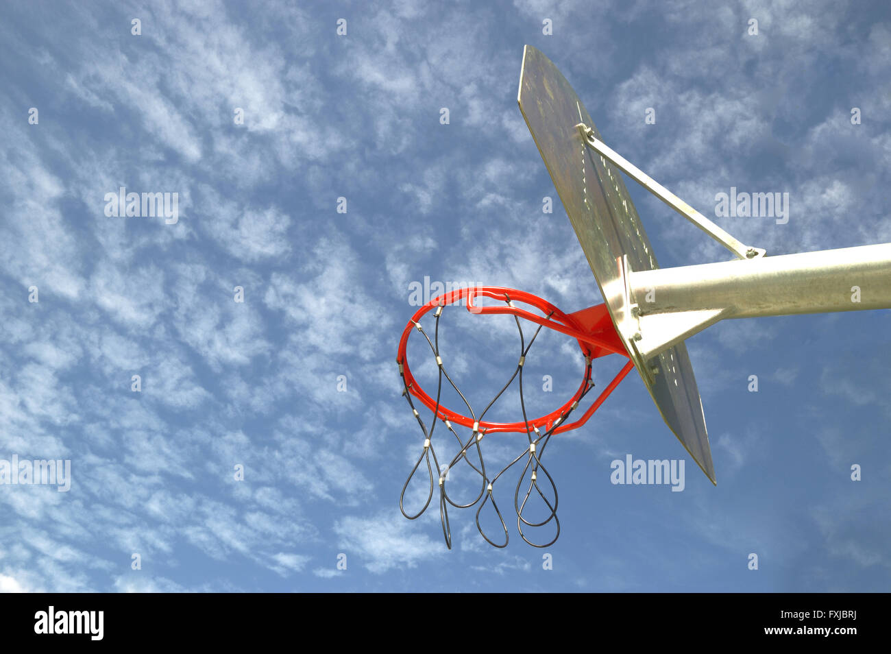 Red basketball hoop against a blue sky in a street park. Empty copy ...