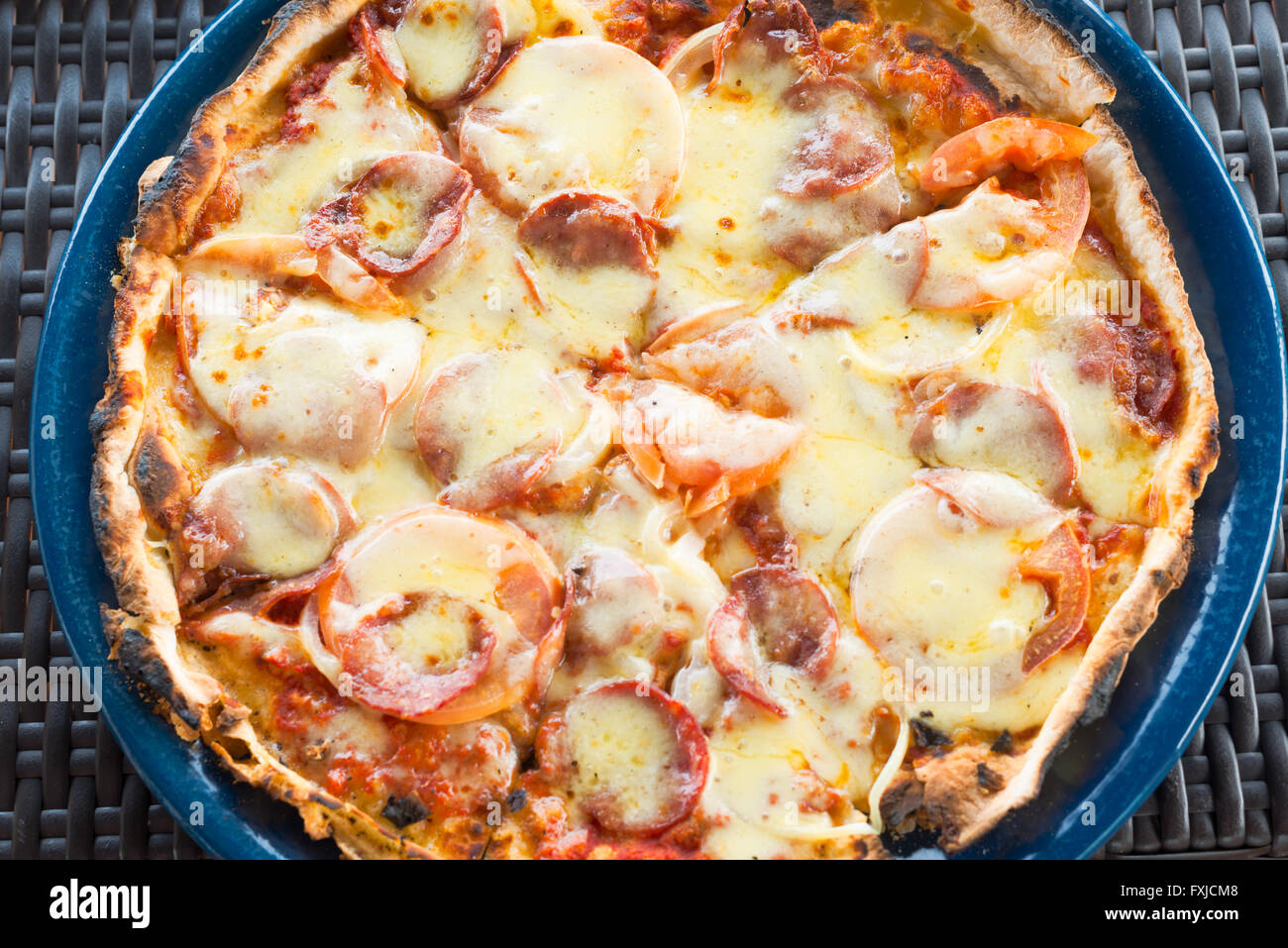 Italian fresh pepperoni pizza top view on a blue plate on wicker table ...