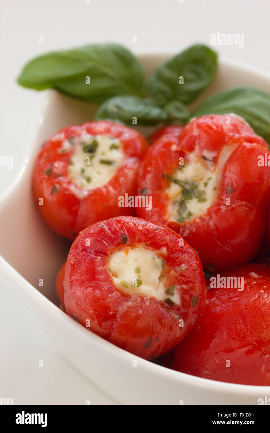 Spicy round red peppers stuffed with cheese, garnished with basil in ...