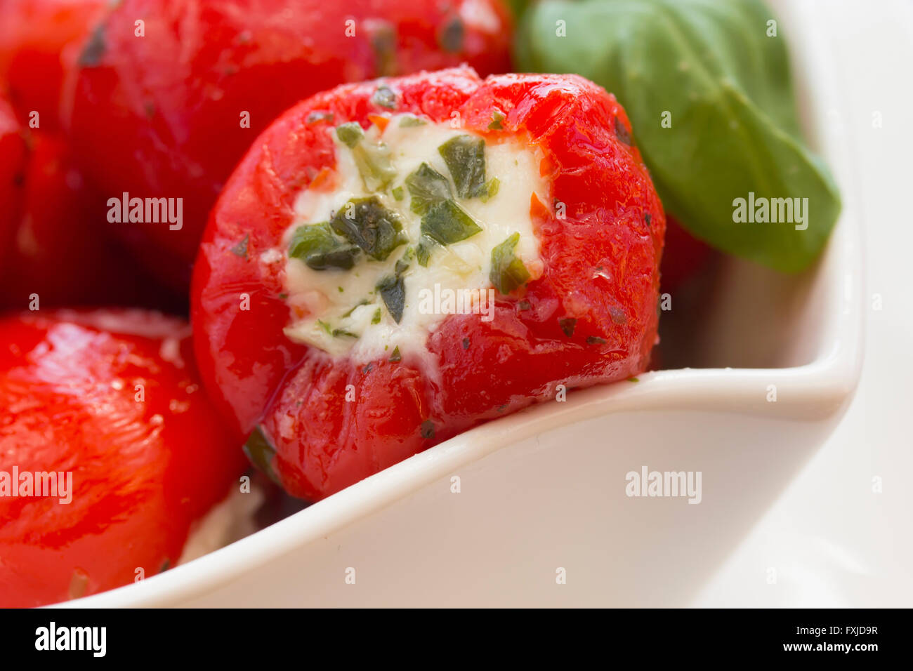 Spicy round red peppers stuffed with cheese, garnished with basil. The ...