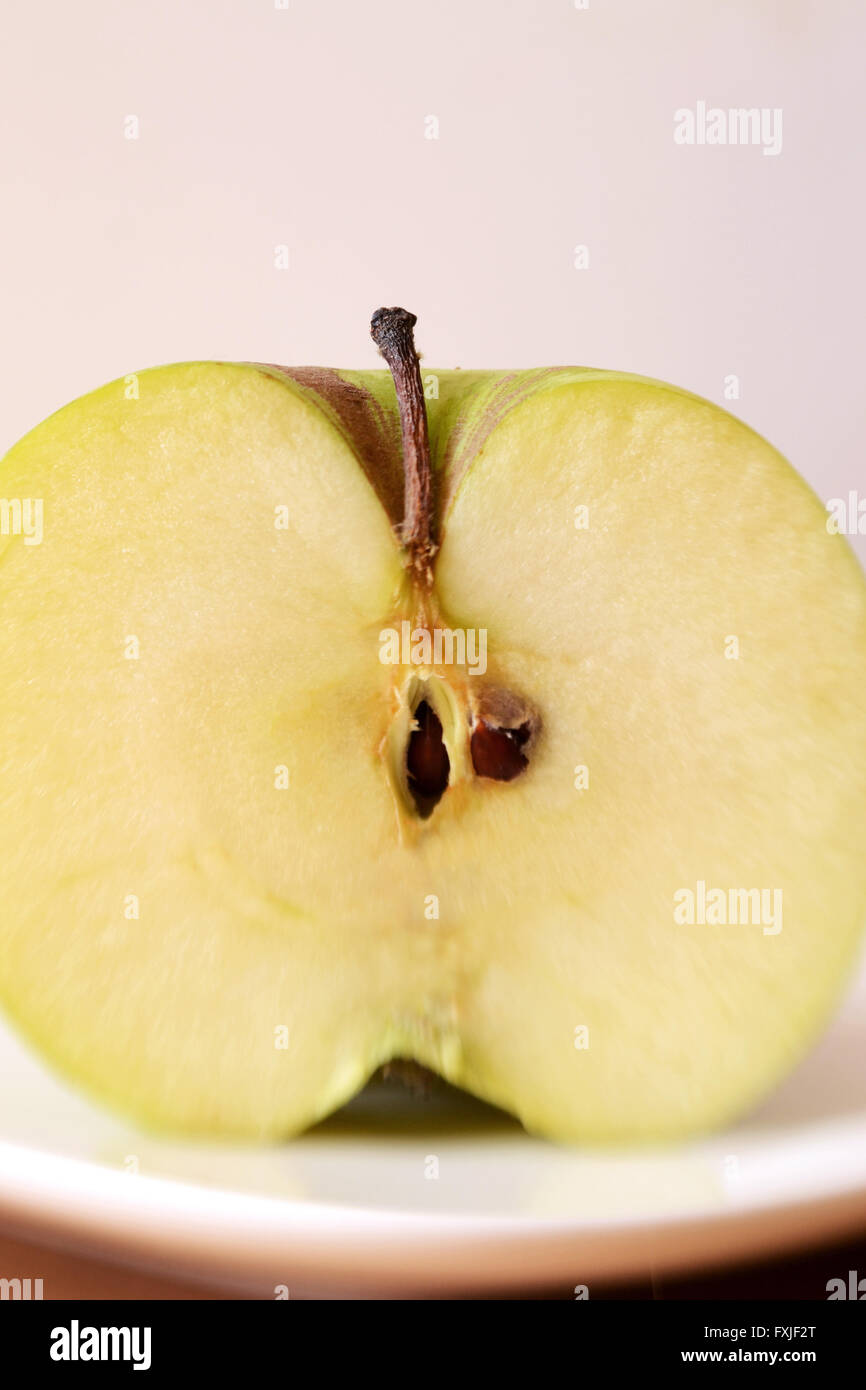Granny Smith apple divided in half, sitting on white plate. Shot with ...