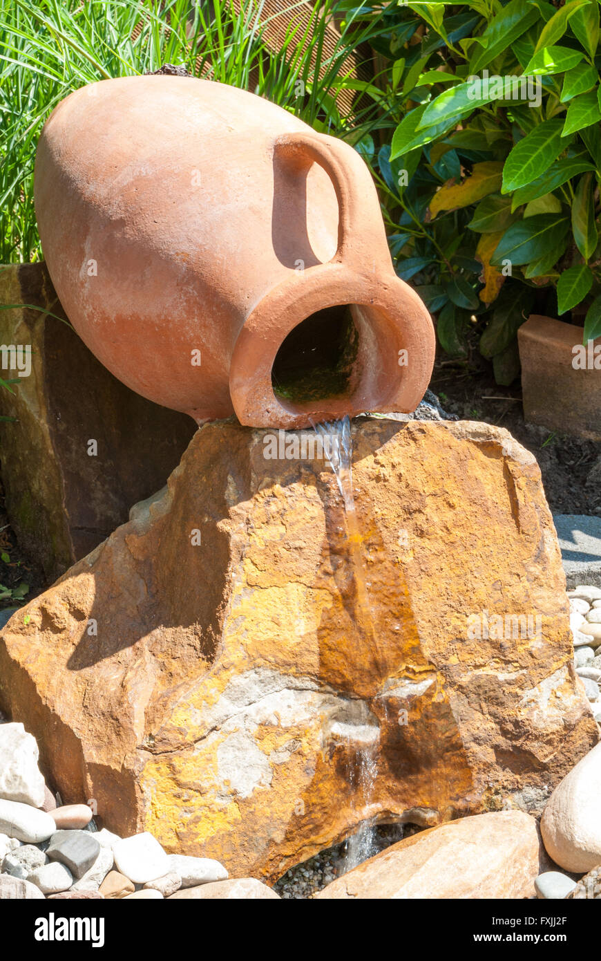 Water feature with an amphora and a bolder in an ornamental garden ...