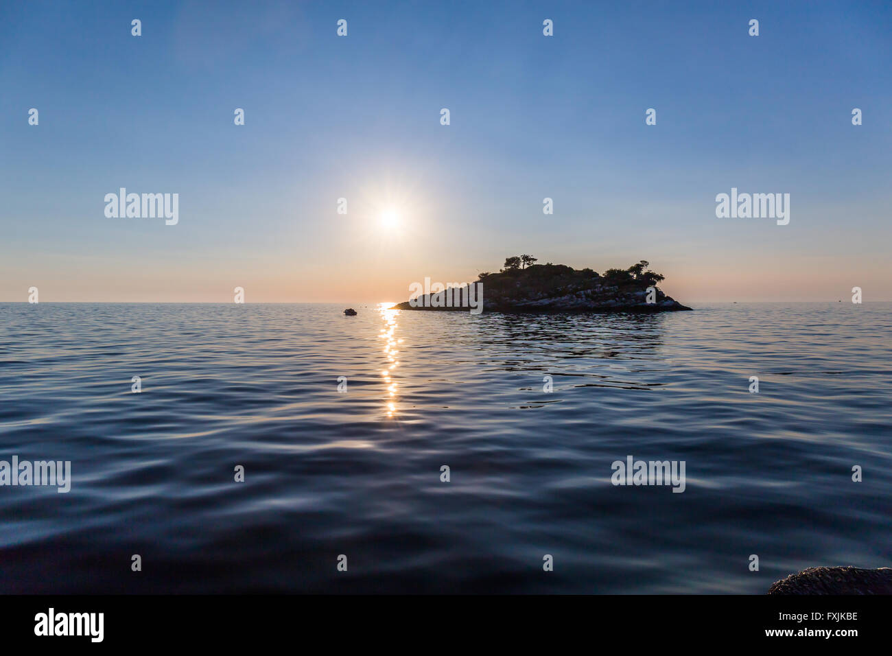 Sea sunset with island and low sun Stock Photo - Alamy