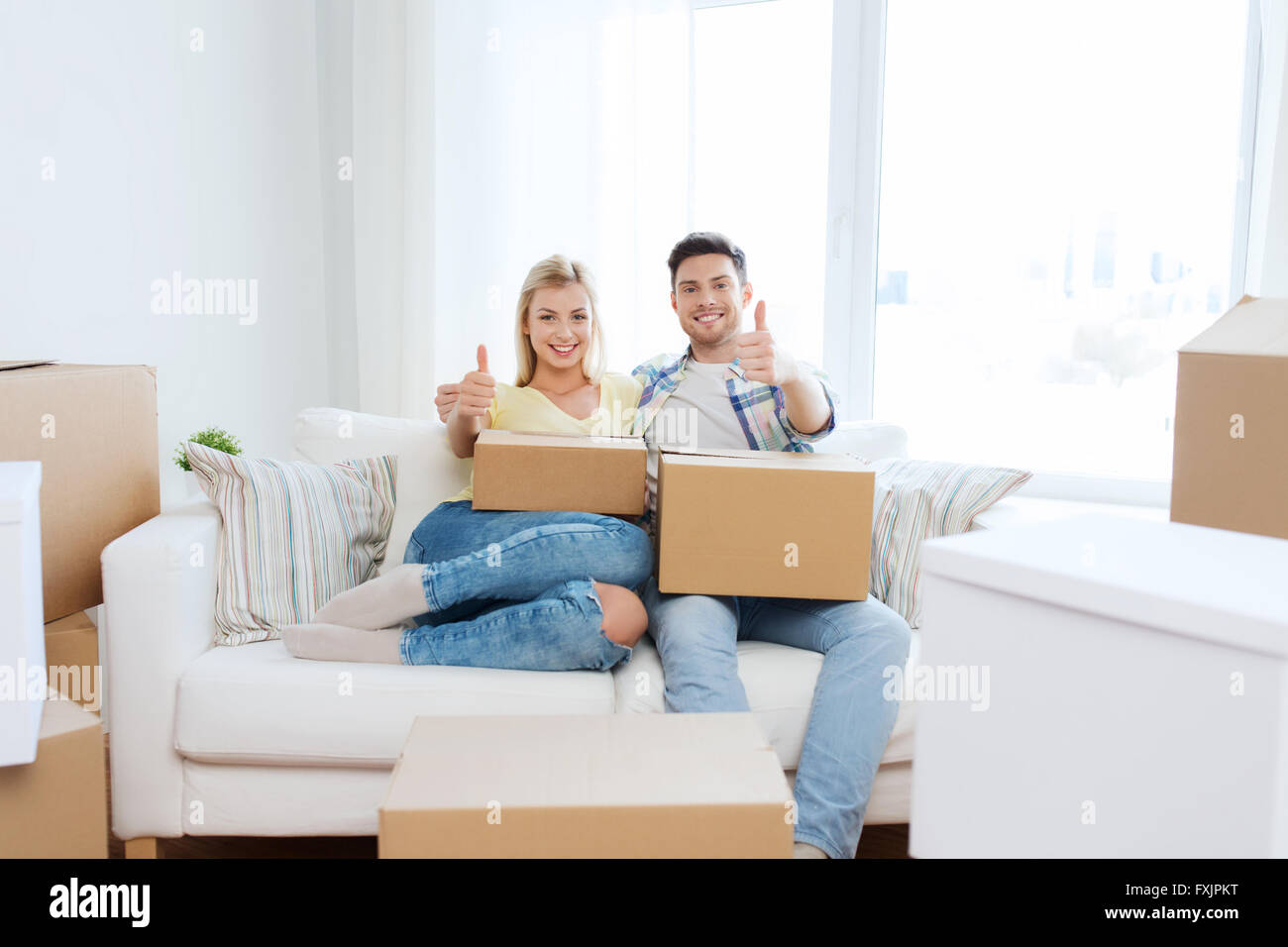 happy couple with boxes showing thumbs up at home Stock Photo - Alamy